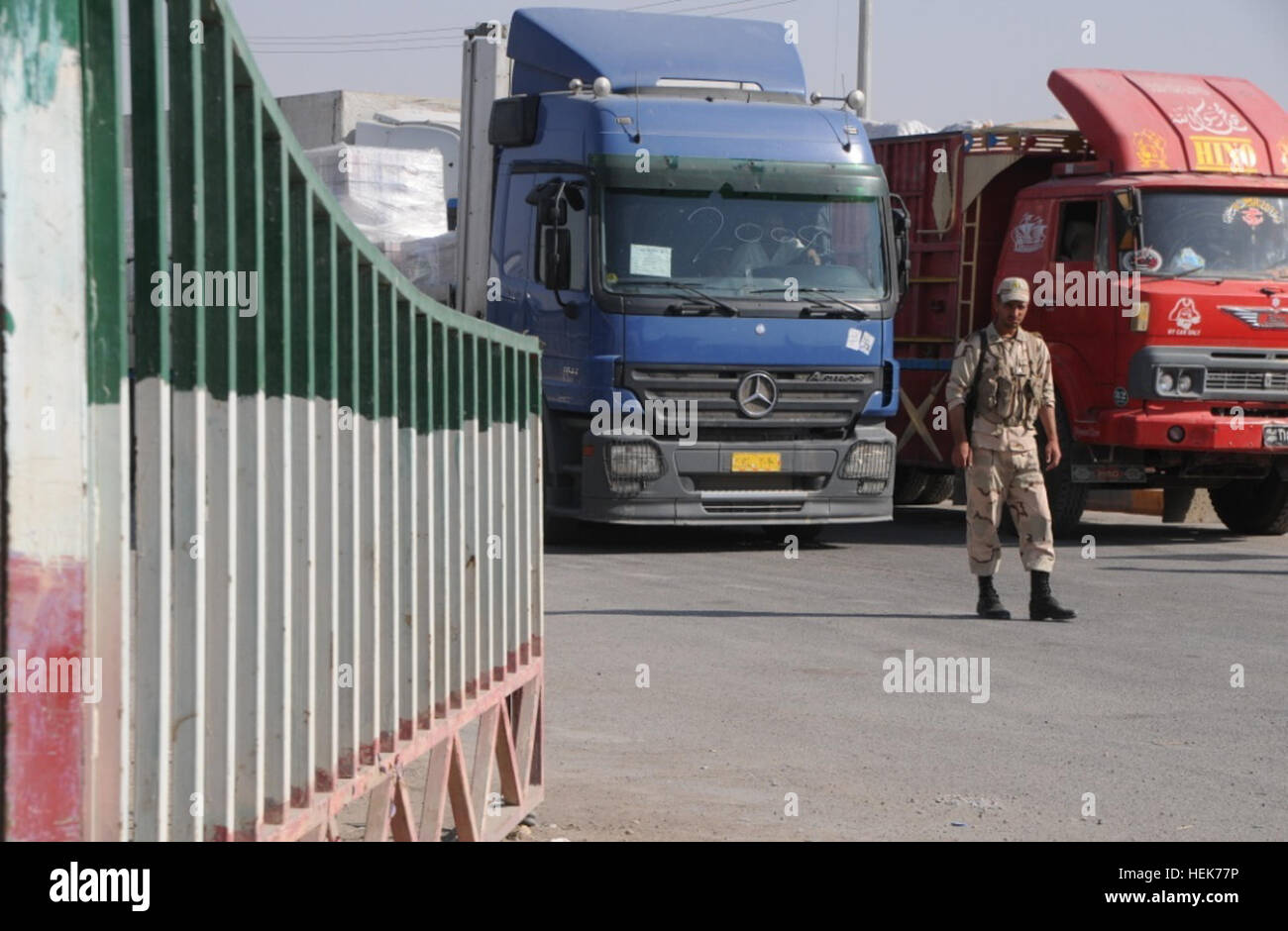 An Iranian border guard supervises the passage of trucks, full of ...