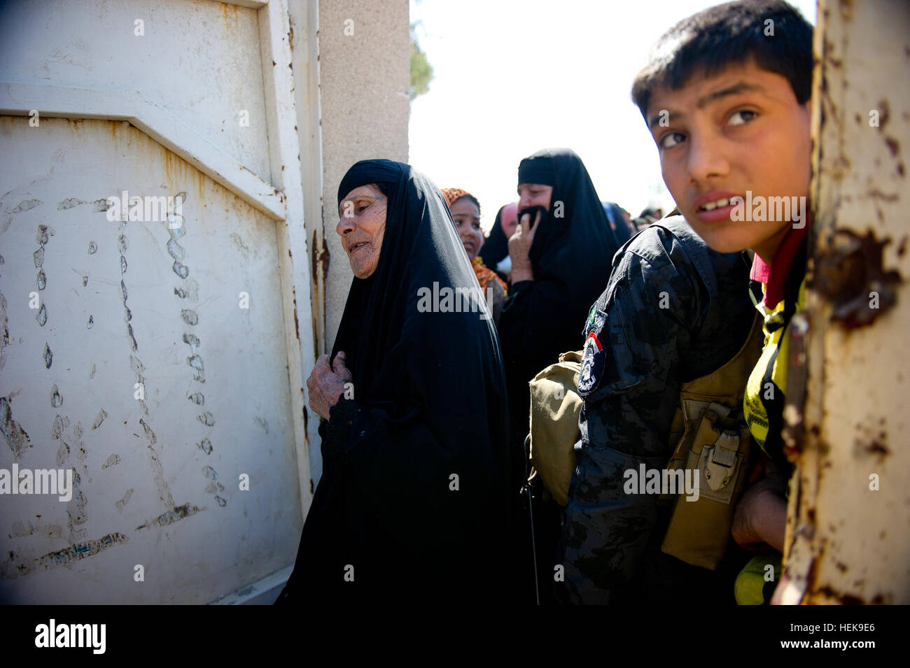 A young Iraqi boy peaks around to look at the line during a ...
