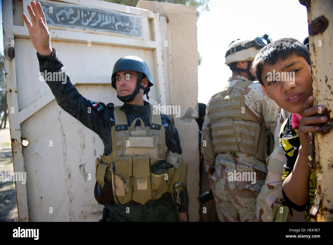 A young Iraqi boy peaks around to look at the line during a ...