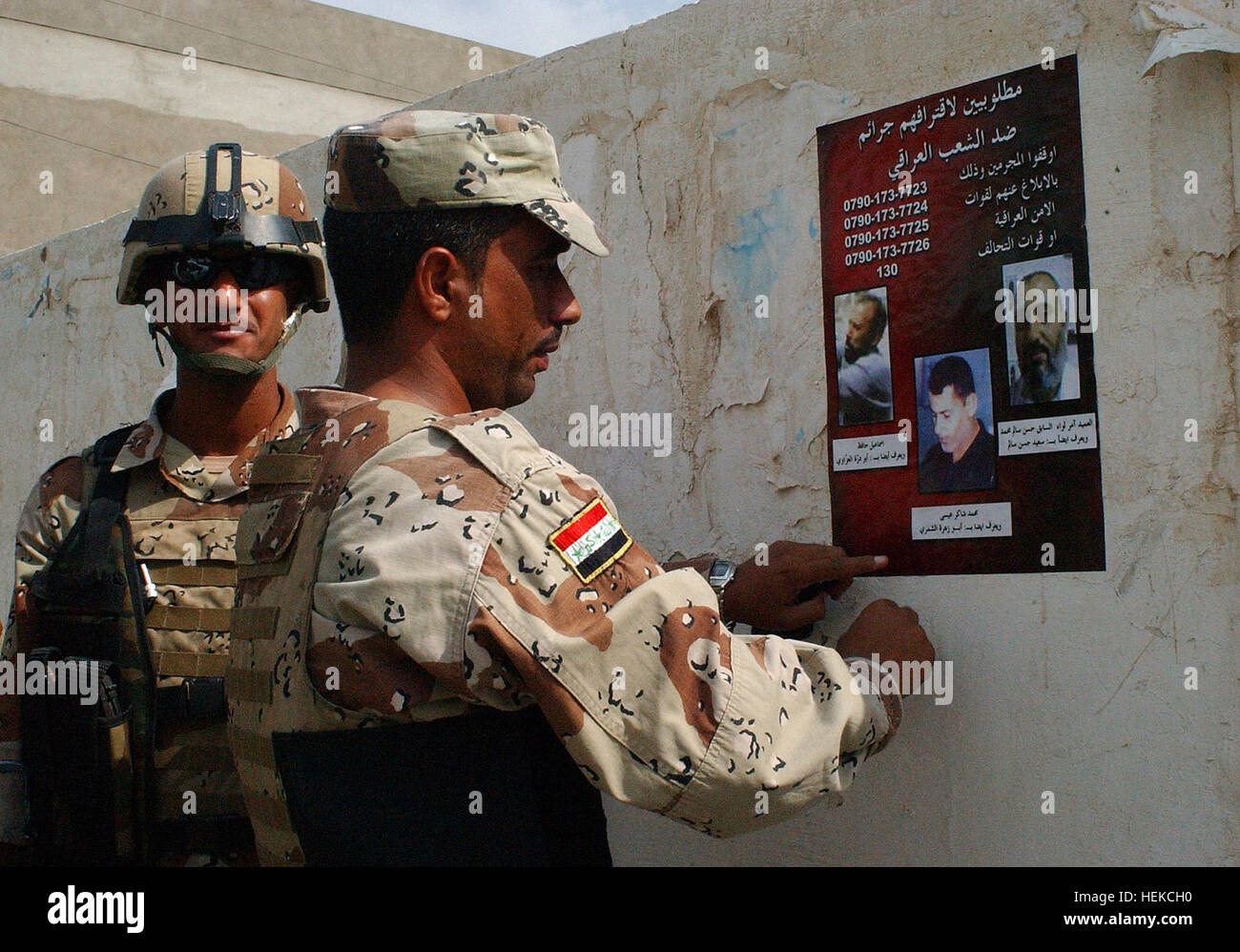 Iraqi army soldiers post wanted signs for insurgents in front of a ...