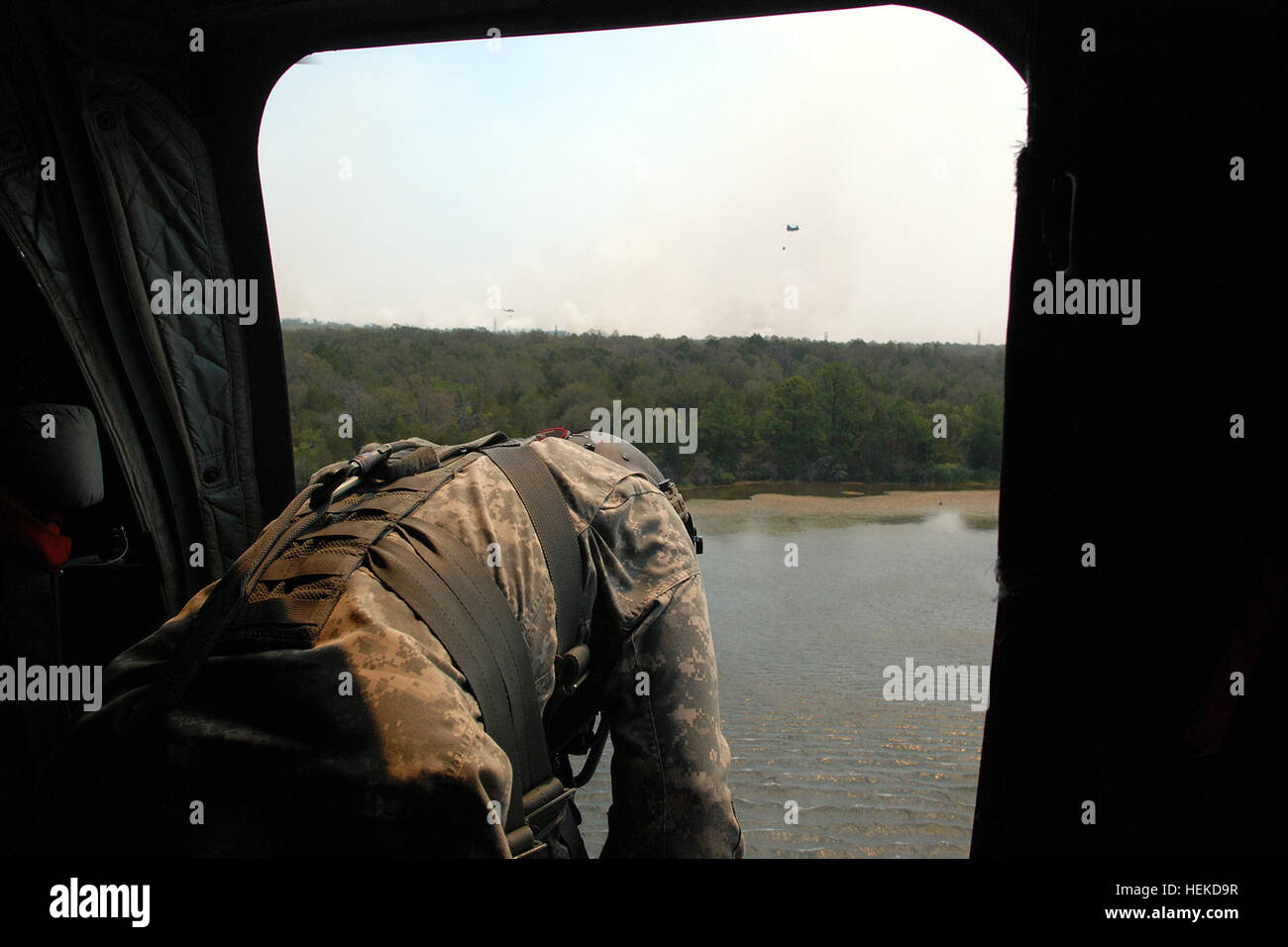 A CH-47 Chinook helicopter crew chief looks down at the water source as ...