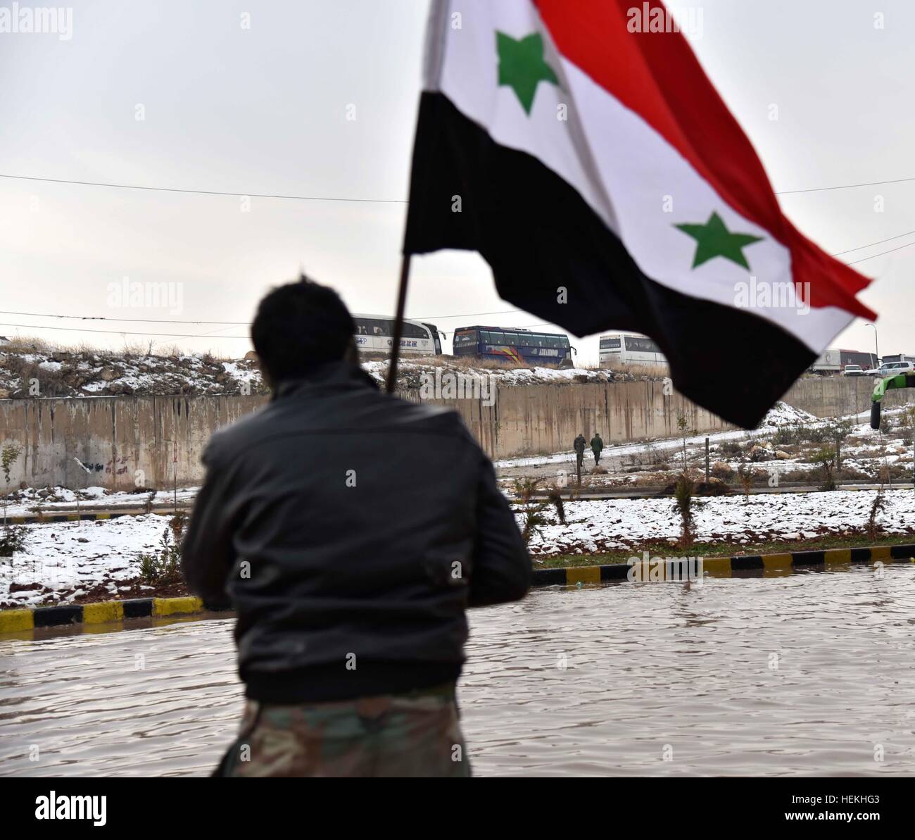 Aleppo, Syria. 22nd Dec, 2016. A man waves a Syrian national flag to ...