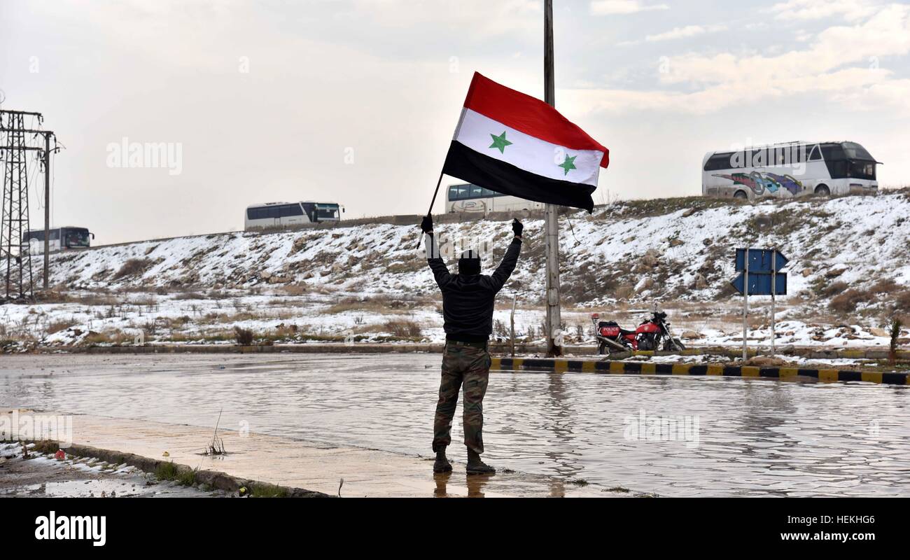 Aleppo, Syria. 22nd Dec, 2016. A man waves a Syrian national flag to ...
