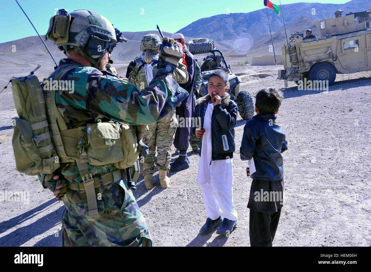 A coalition special operations forces member gives a pen to a young boy ...