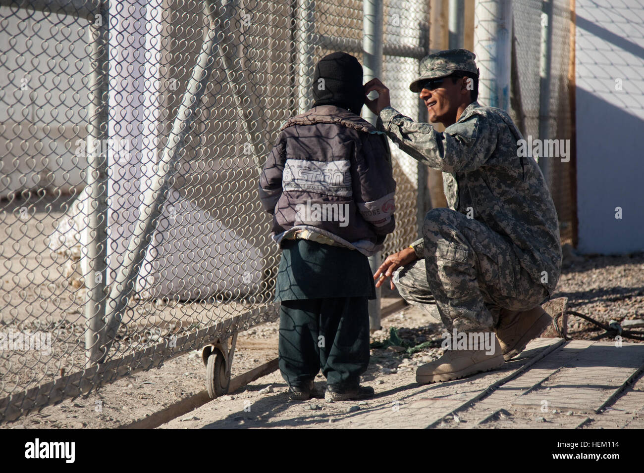 An interpreter with the U.S. Army adjusts the cap of an Afghan boy near ...