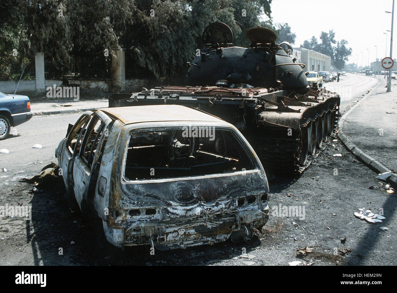 A burned civilian automobile and an Iraqi T-55 main battle tank lie ...