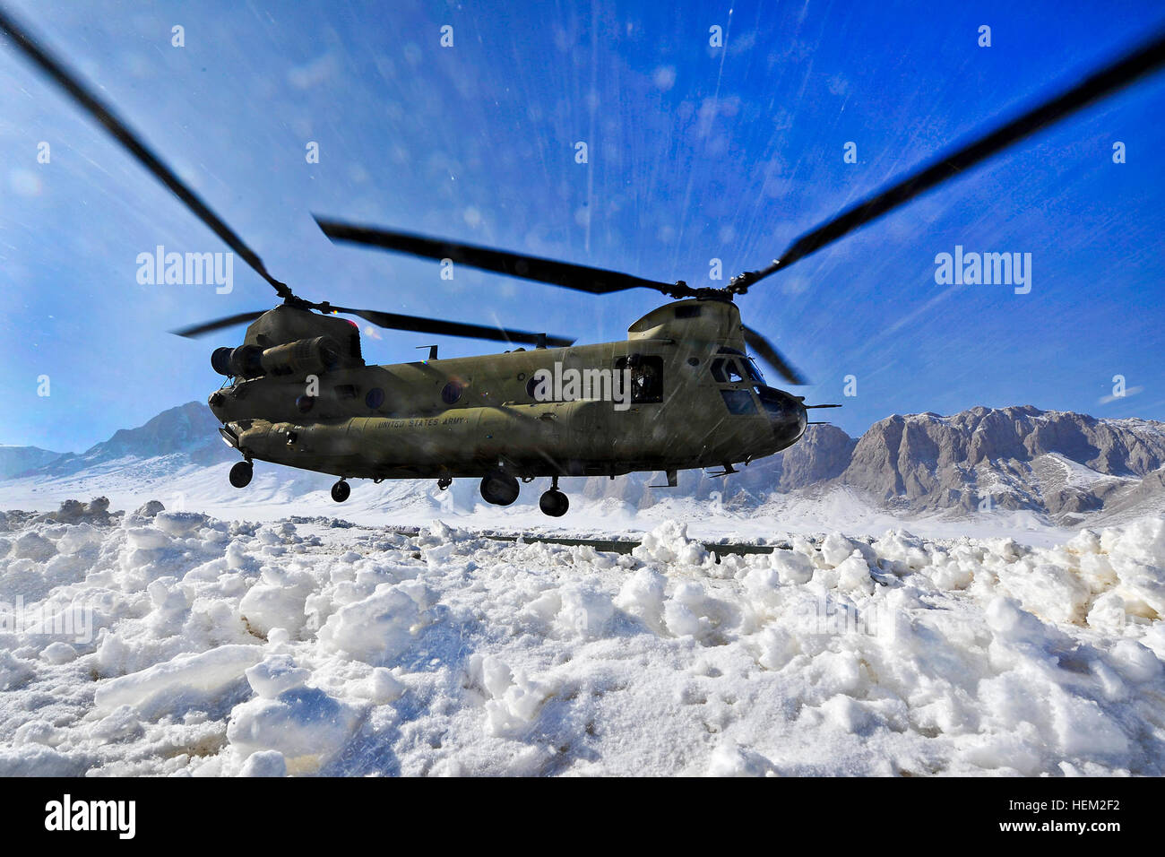 A CH-47 Chinook helicopter raises a white out of blowing snow as it ...