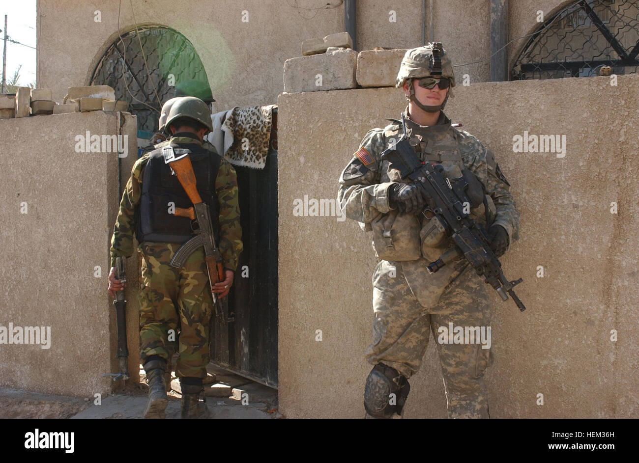 Iraqi National Police enter a house while U.S. Army Specialist Craig ...