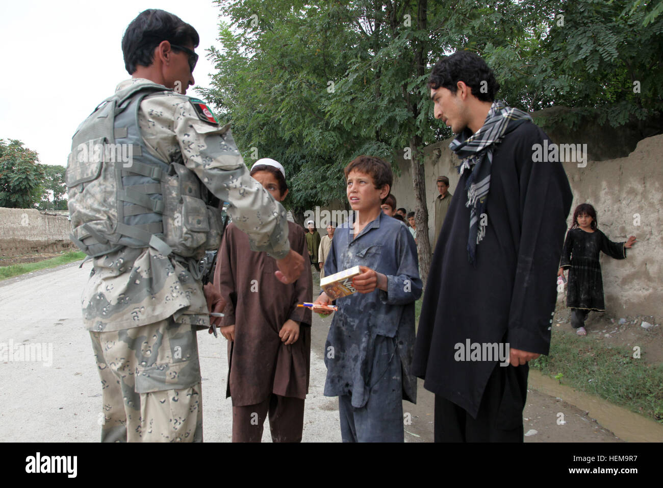 An Afghan Border Police (ABP) officer, left, hands out pens and a snack to an Afghan boy in Ayub ...