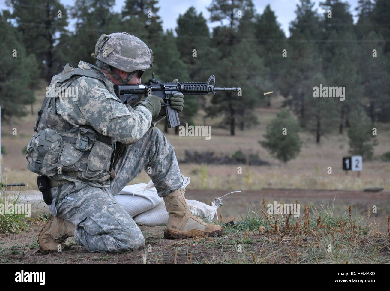 A soldier demonstrates firing an M16 A2 rifle at the kneeling position ...