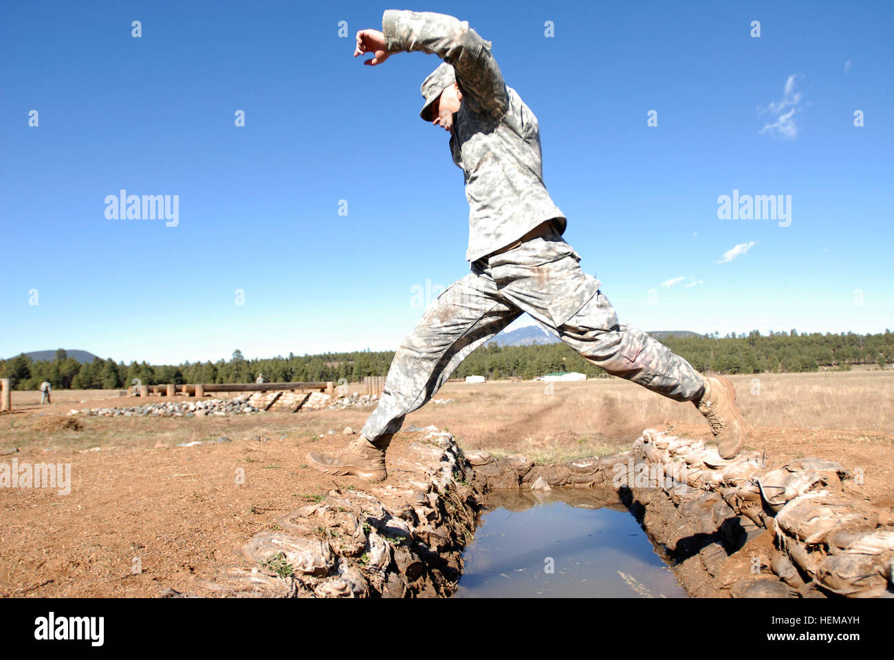 A guard member jumps over a ditch filled with water and mud during the ...