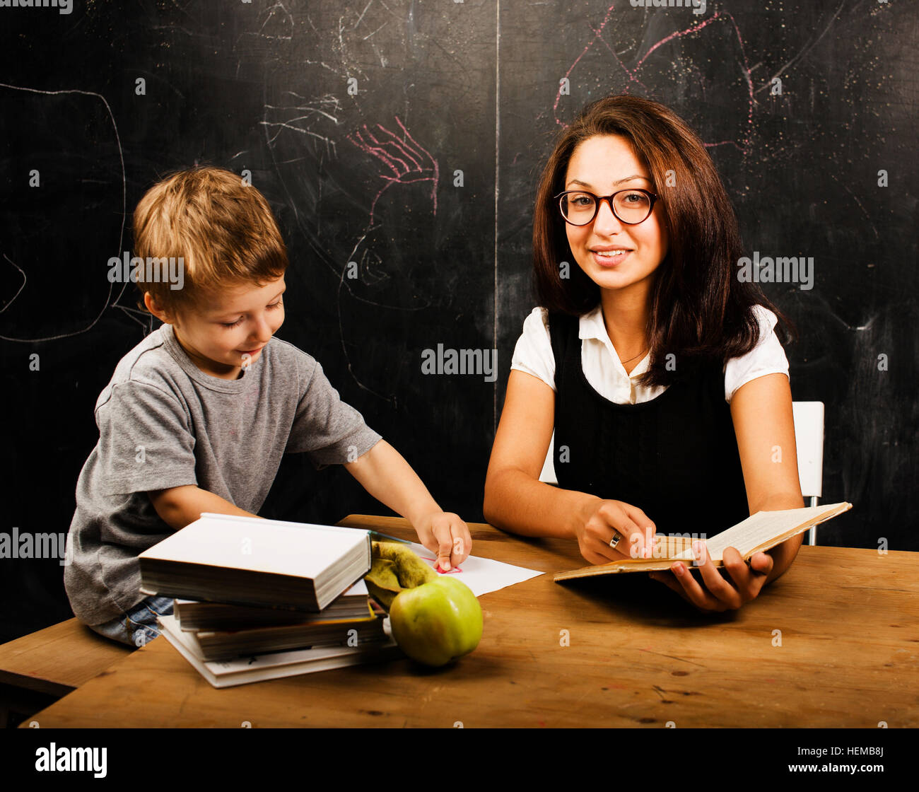 little cute boy with young teacher in classroom studying at blac Stock ...