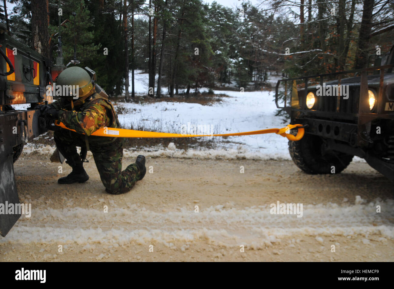 A Romanian soldier attaches a tow strap to a Humvee during a military ...