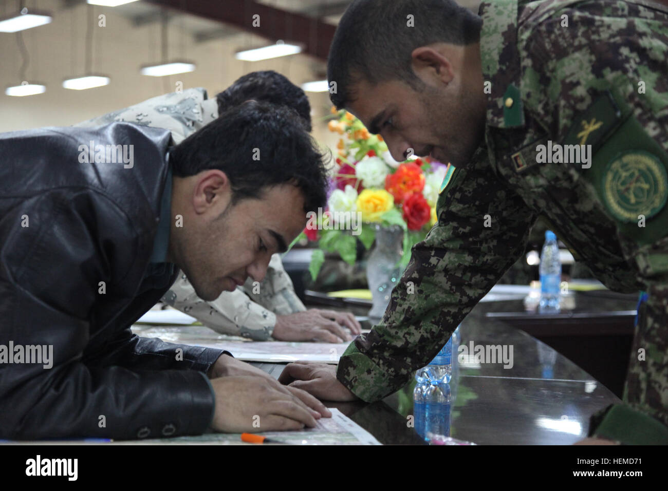 An Afghan National Policeman gets help plotting points on a map from a ...