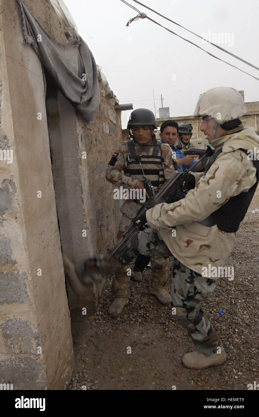 An Iraqi army soldier kicks in the door to a building on an IA compound ...