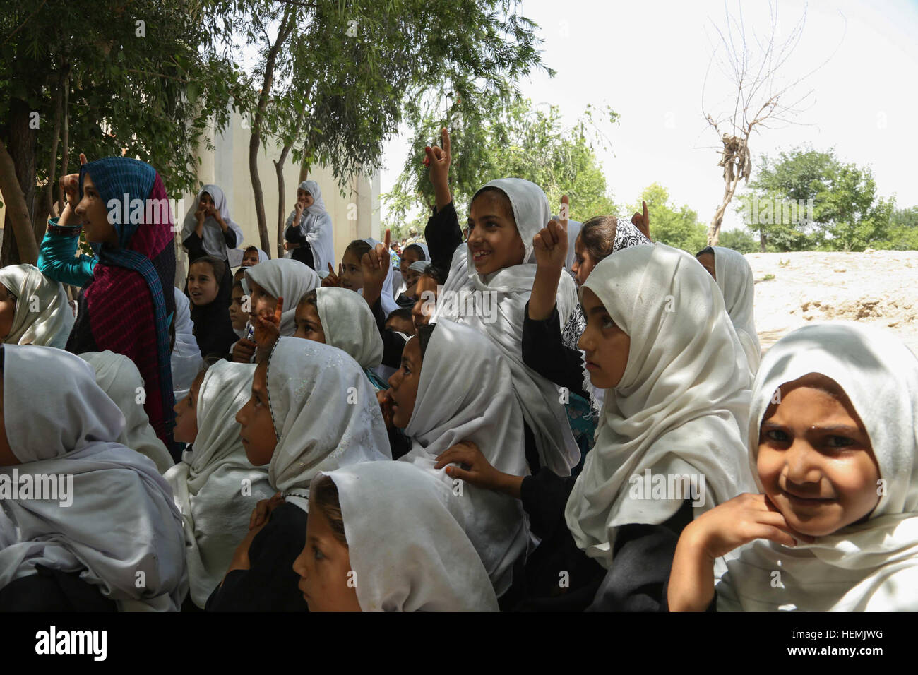 School girls sit waiting outside after class to receive school supplies ...
