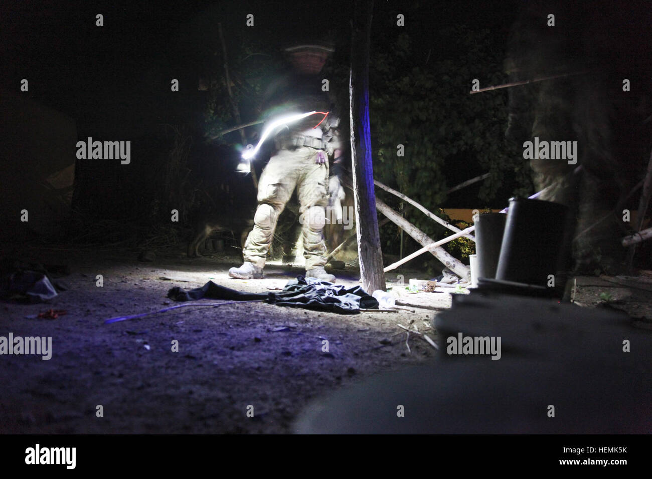 A coalition security force member searches for homemade explosive ...