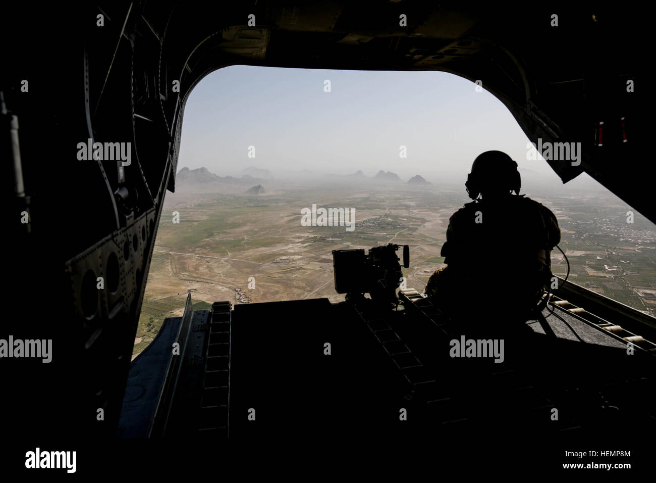 A U.S. Army CH-47 Chinook helicopter crew chief sits at the ramp of the ...