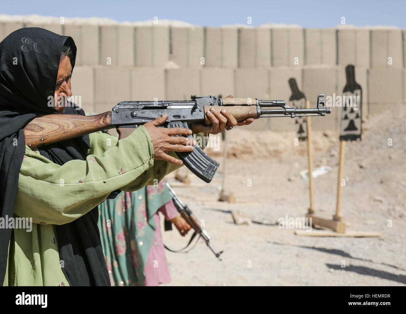 A female Afghan Uniformed Police member aims an AK-47 rifle and places ...