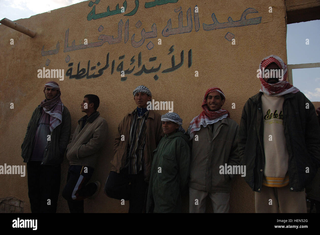 A group of young Iraqi boys and men stand by and observe U.S. Army ...