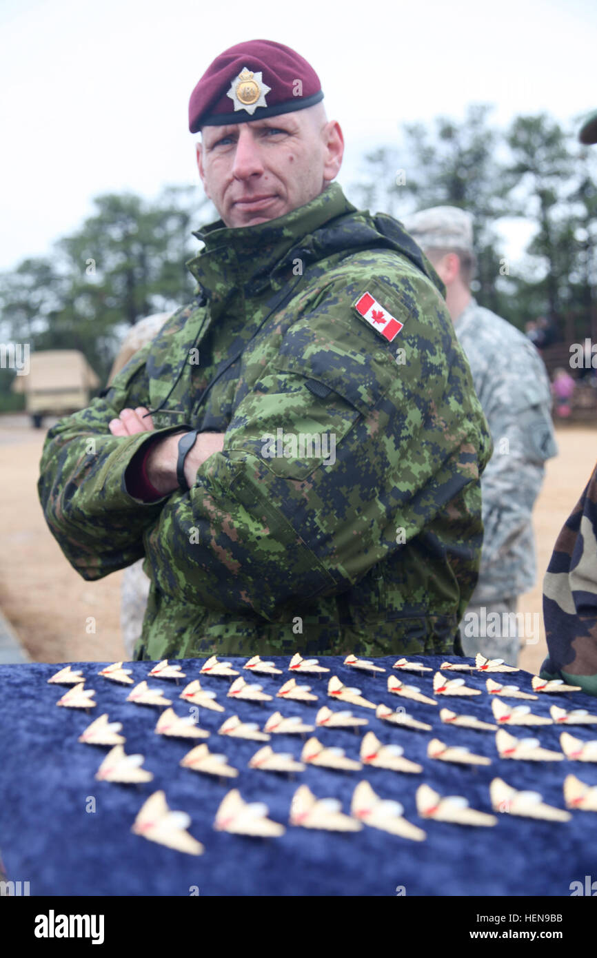 A jumpmaster from Canada stands next to a tray of Canadian jump wings ...