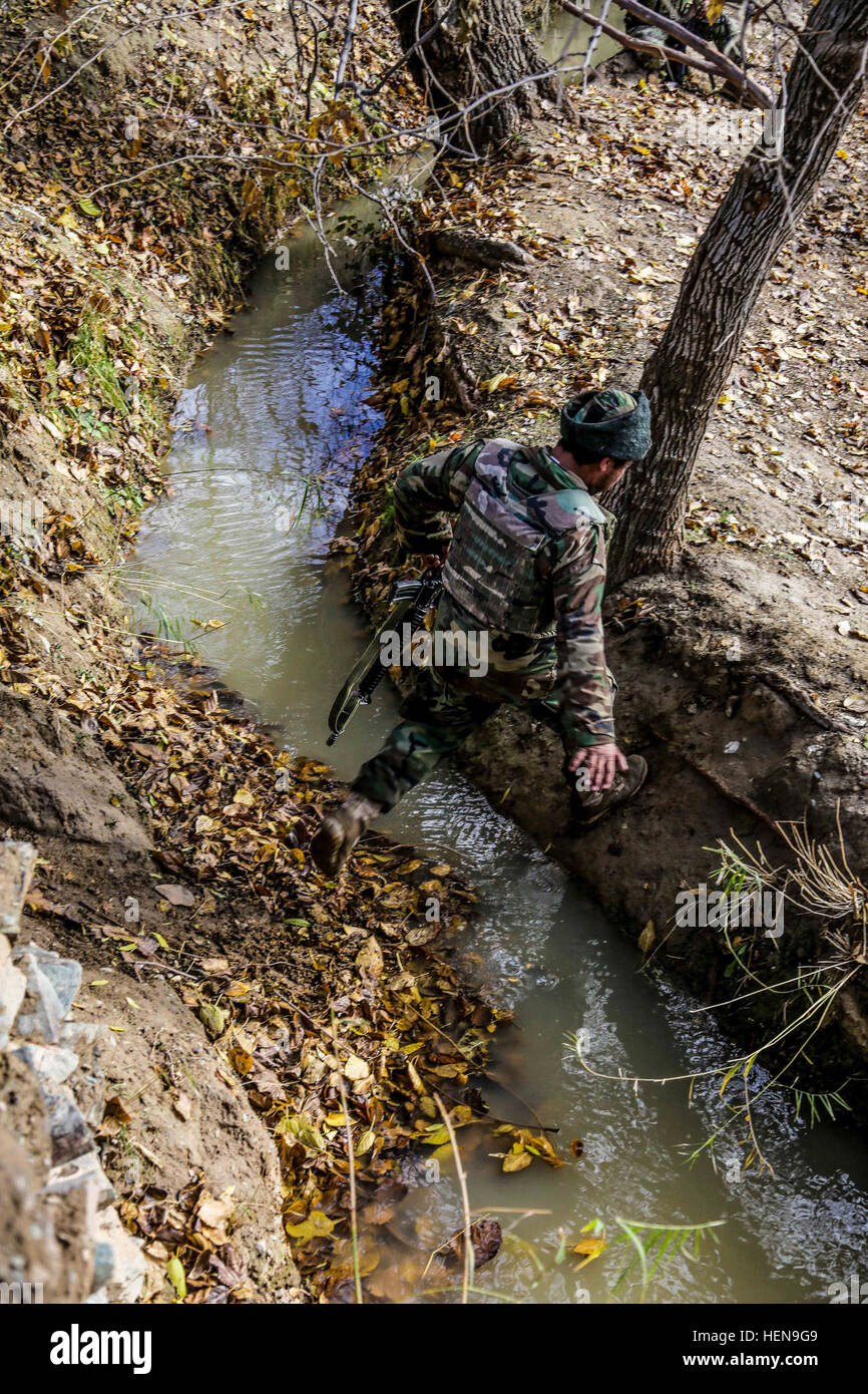 An Afghan National Army soldier leaps over a trench during a clearance ...