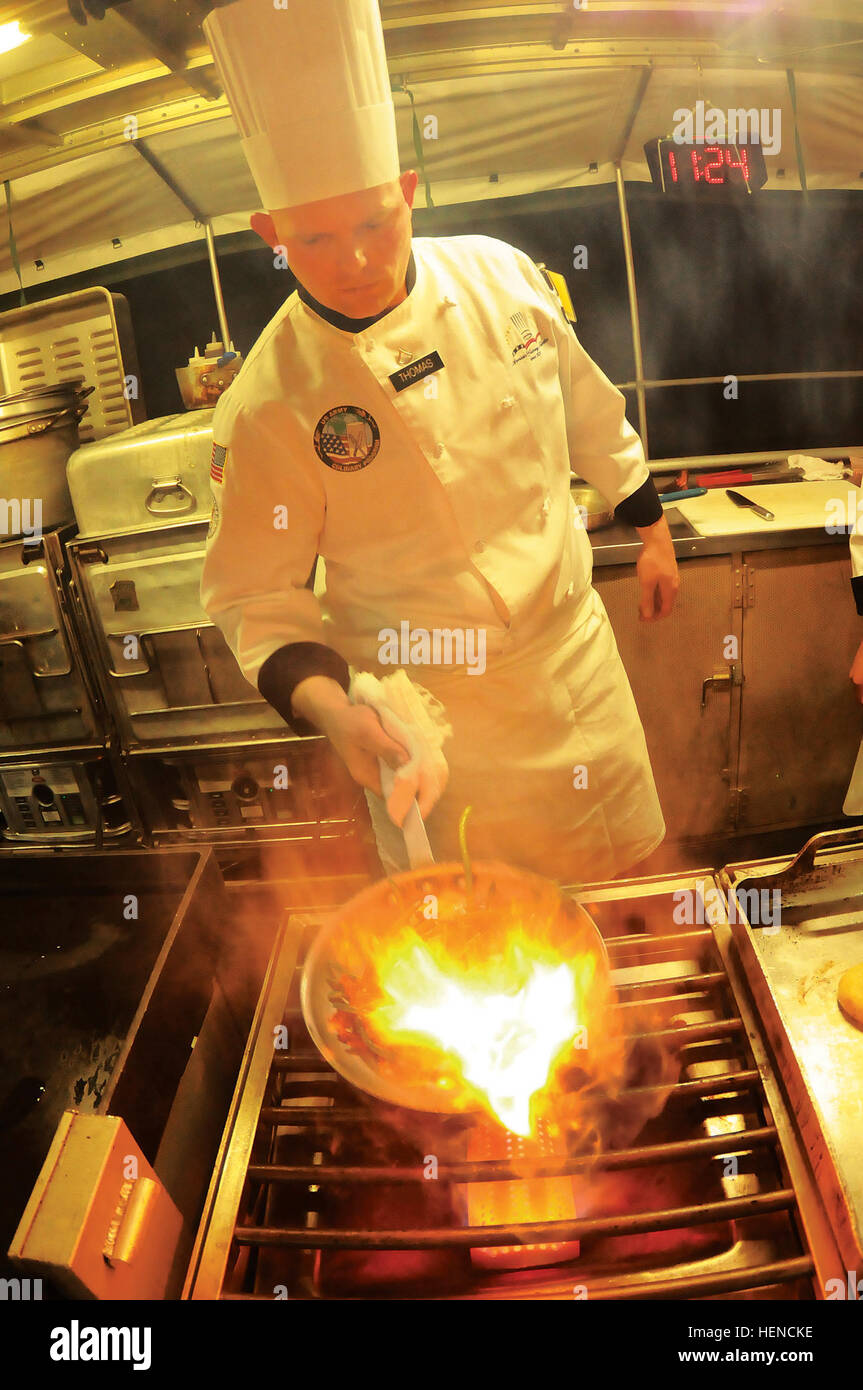 A competitor heats up a pan during the Military Hot Food Competition ...