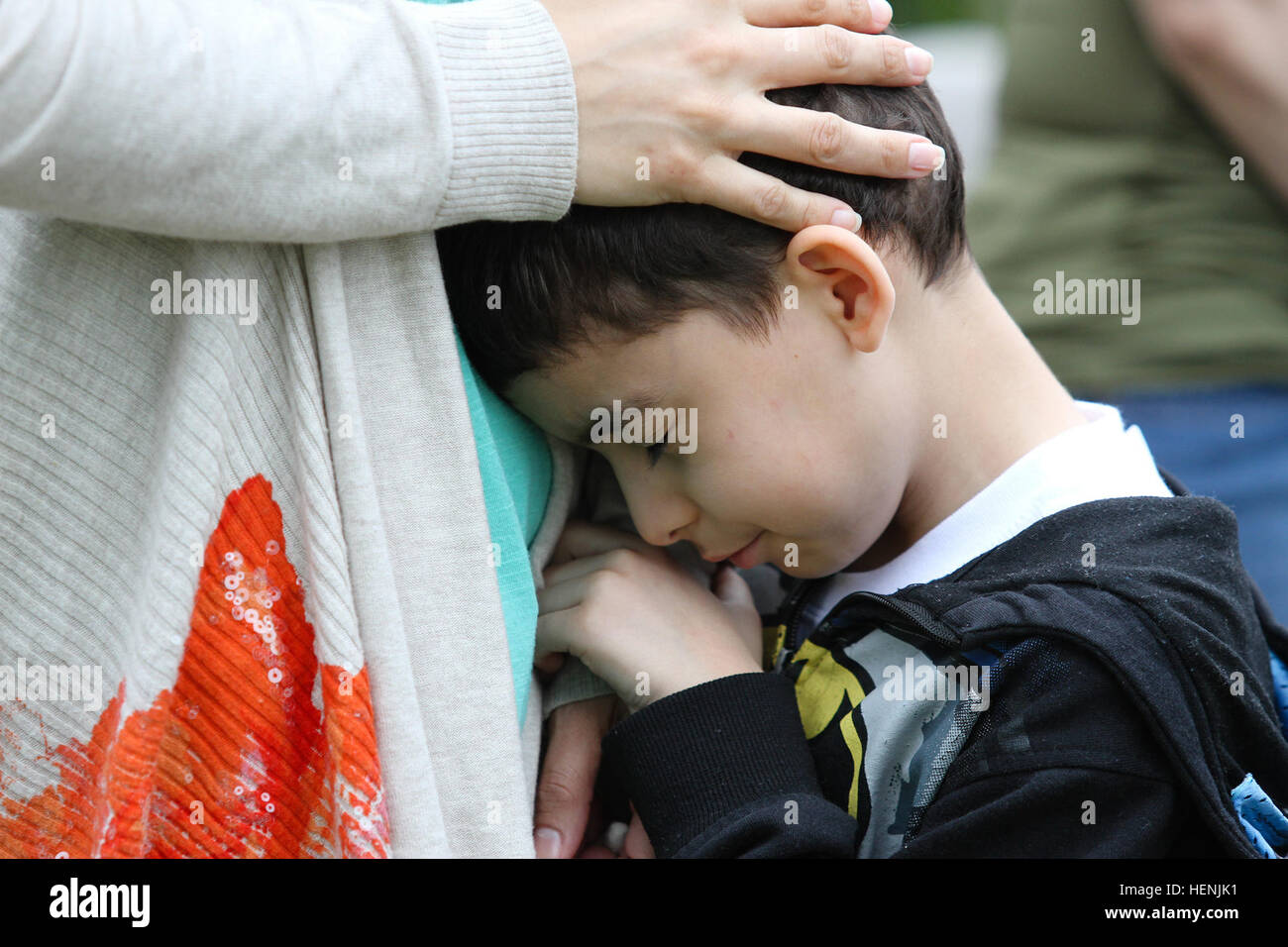A young boy is comforted by his mother during a departure ceremony for ...