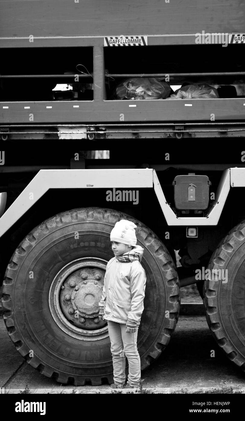 A Lithuanian child stands beside a military vehicle while other local ...
