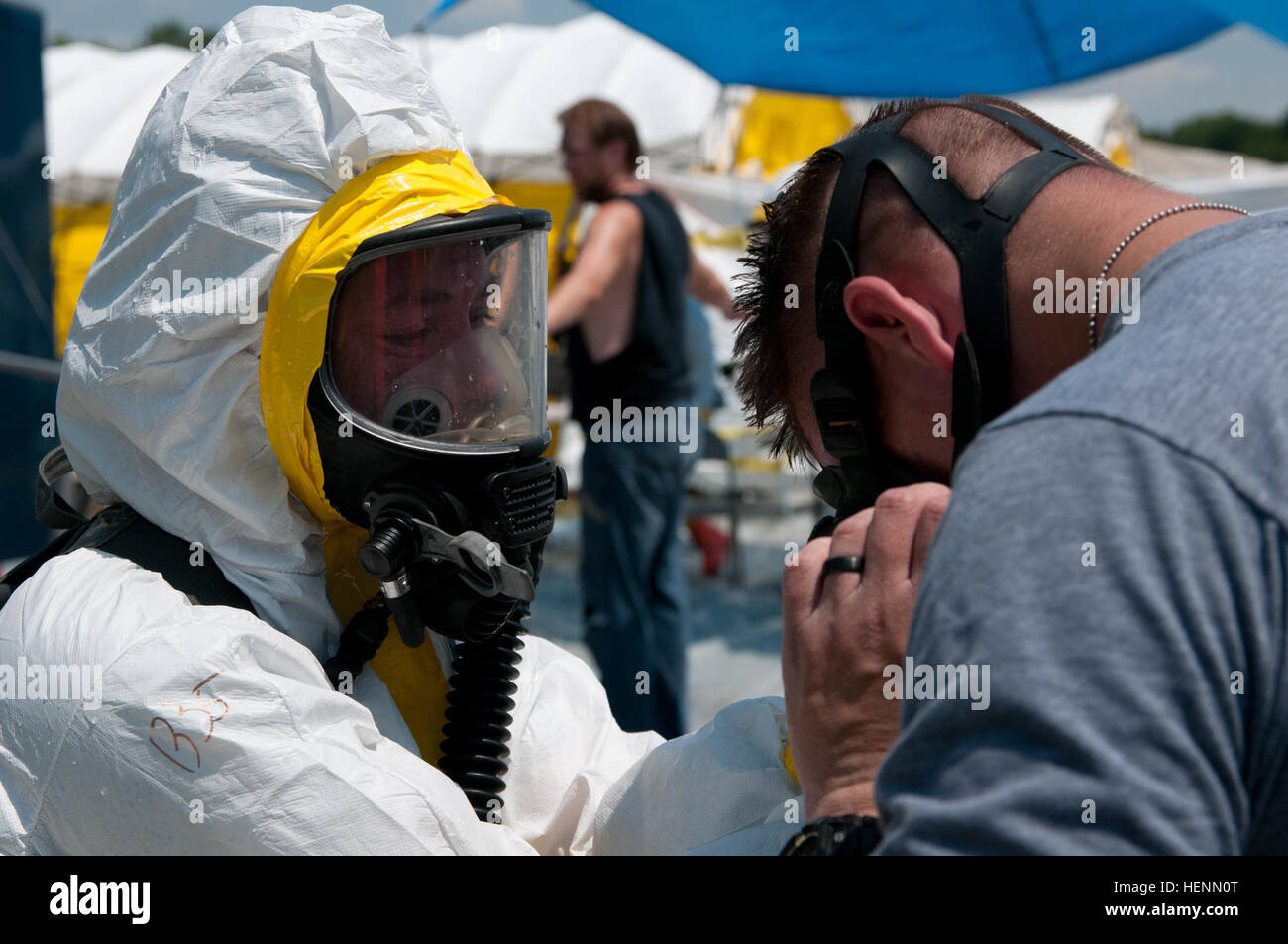 One Soldier helps another remove his gas mask on a decontamination lane ...