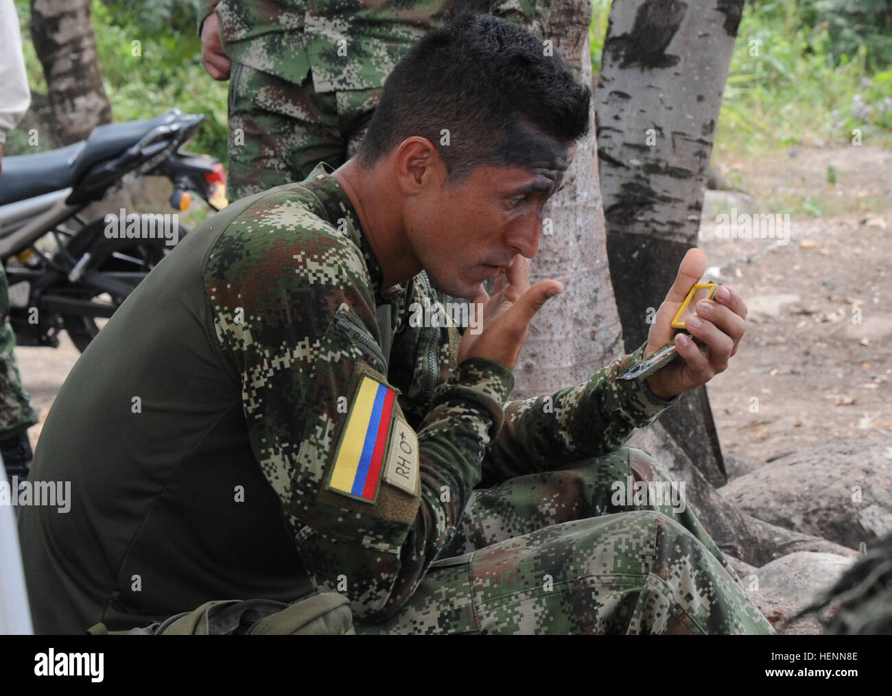 A Colombia special operations sniper applies camouflage face paint ...