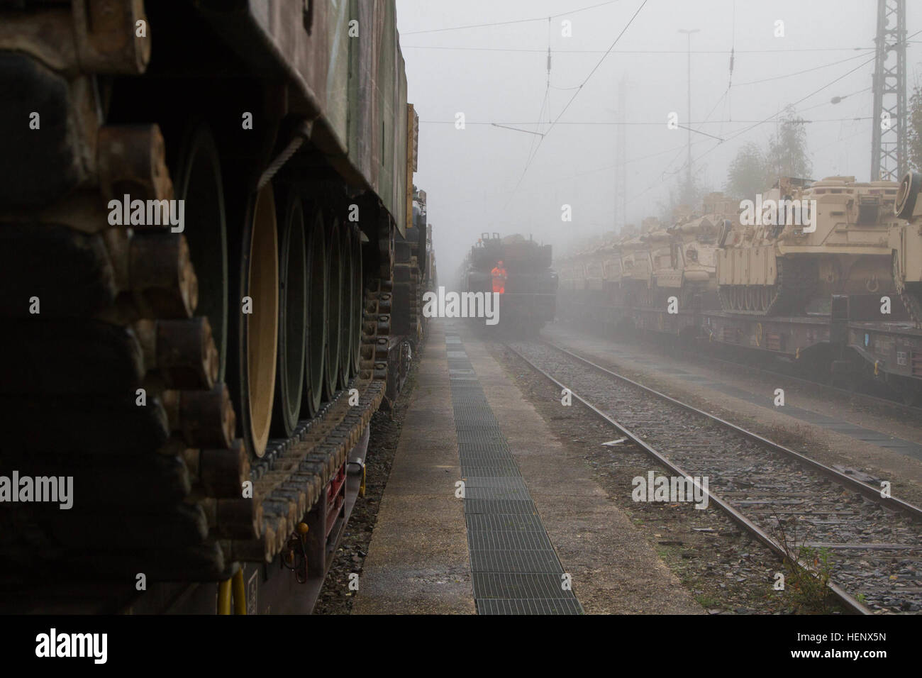 A German train worker guides a train carrying U.S. Army M1A2 Abrams ...