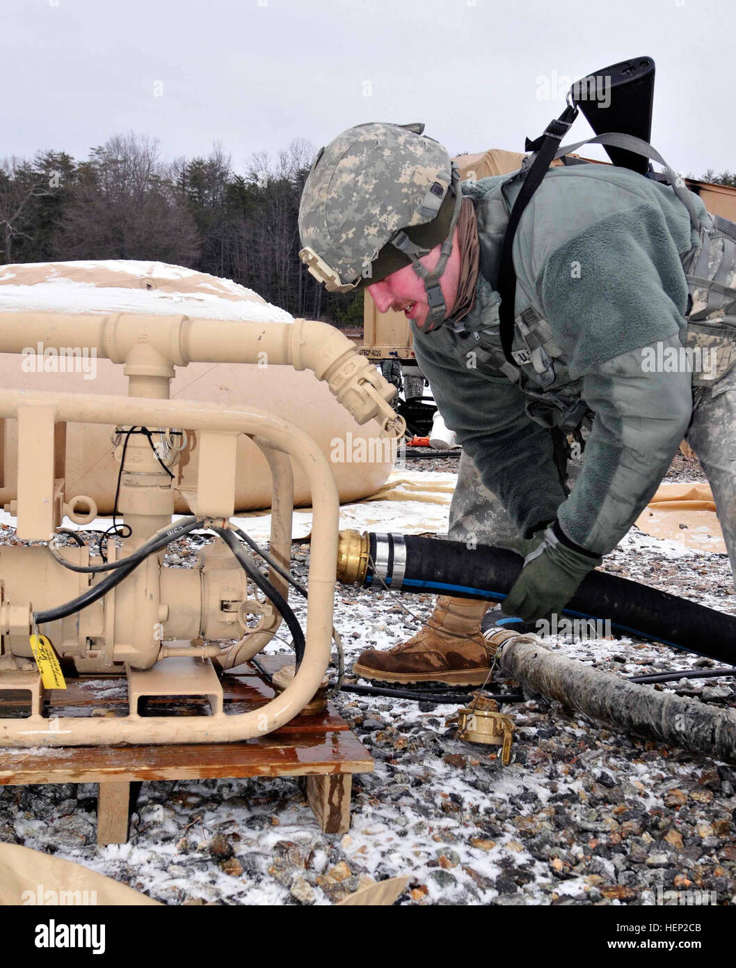Spc. Ryan Poling attaches a water hose to a pump in preparation for ...