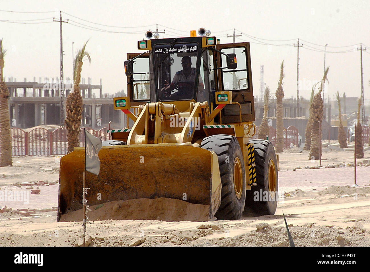 An Iraqi construction worker operates a bulldozer, as the moves sand ...