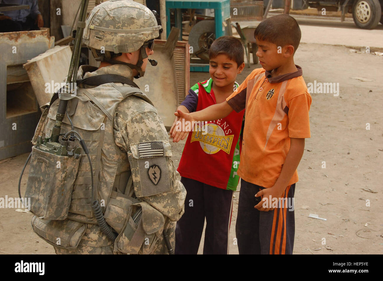 Spc. Gregory Kastner, a native of Excelsior, Minn., greets two Iraqi ...