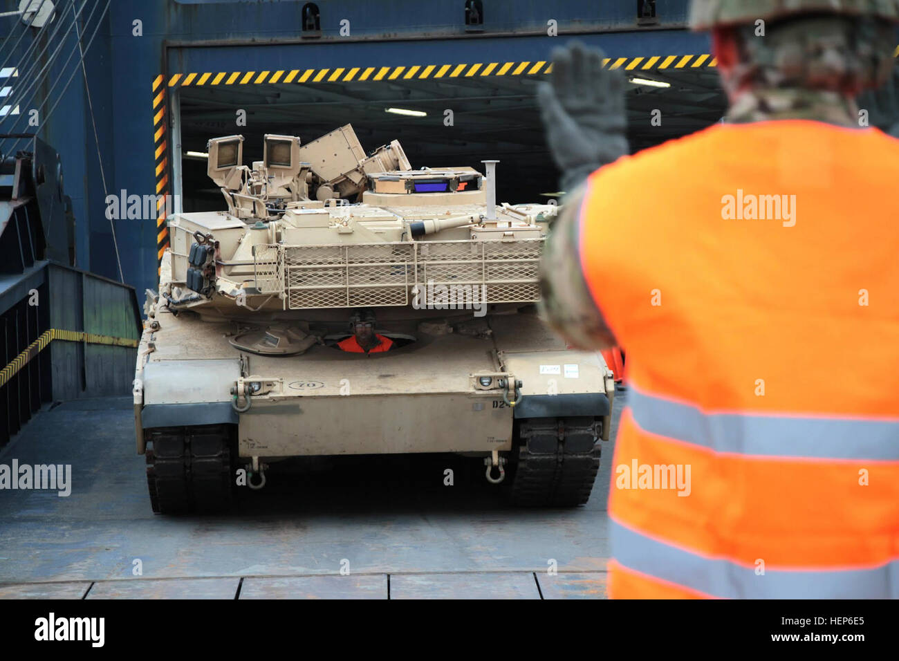 A U.S. Army soldier guides an M1A2 Abrams tank off a transport vessel ...
