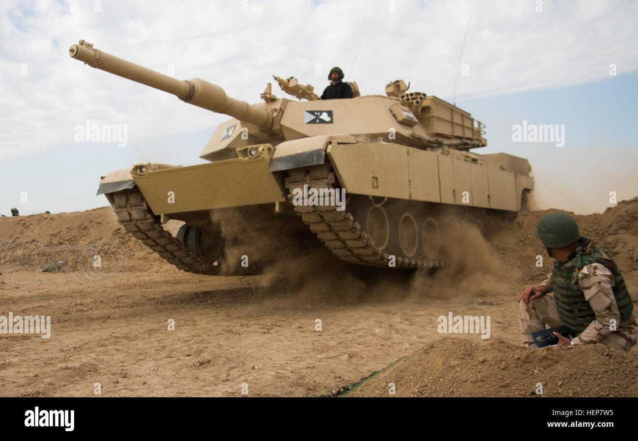 An Iraqi Army tank clears an obstacle while an Iraqi Army Soldier the ...