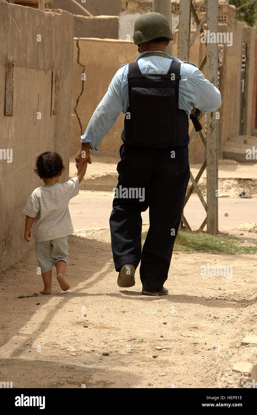 An Iraqi police officer escorts a small child back to her home during a ...