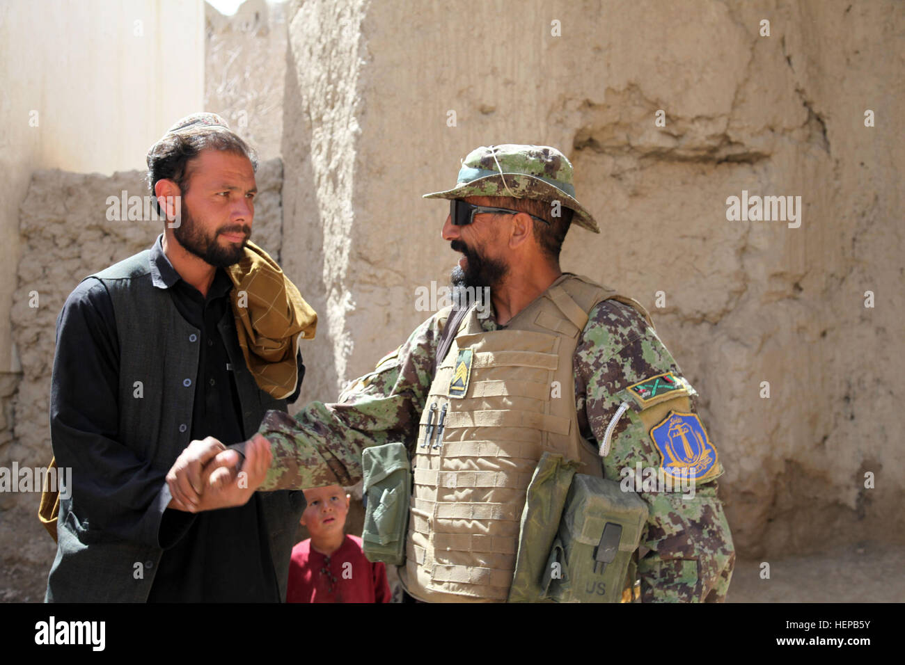 An Afghan National Army soldier shakes hands with a resident of the ...