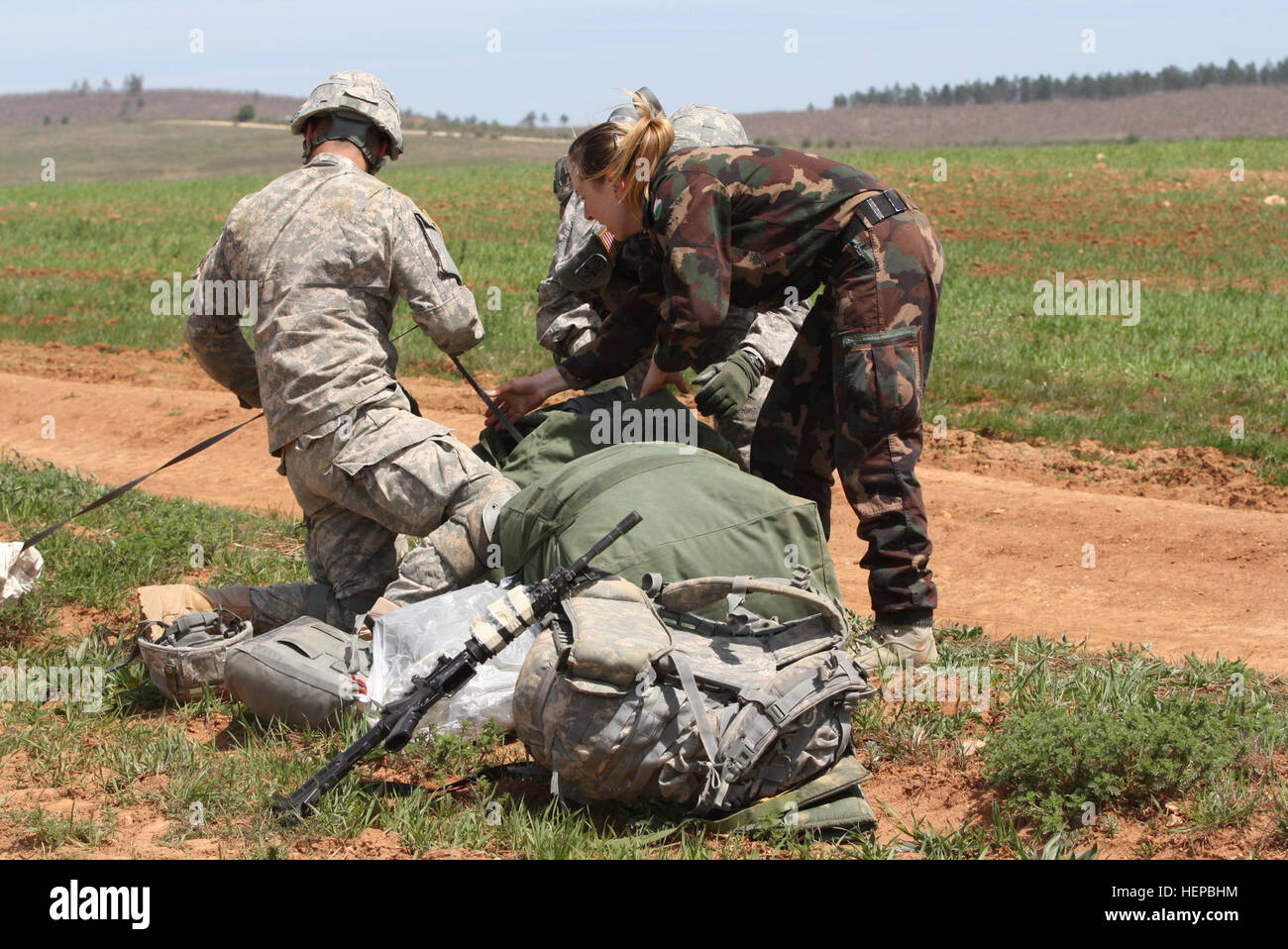 A U.S. Army paratrooper helps a Hungarian army paratrooper load her ...