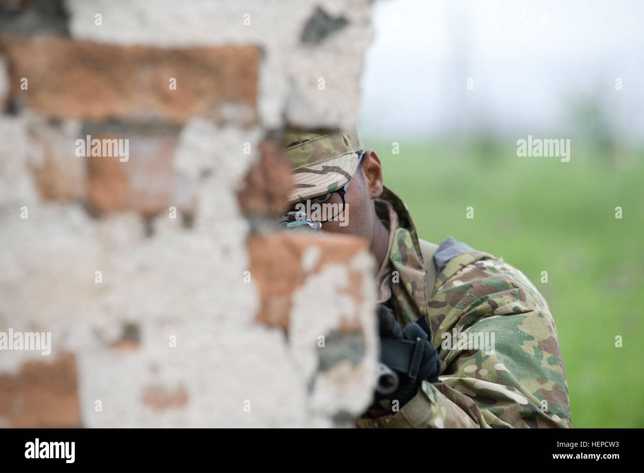 A U.S. Soldier peers around a corner as his four-man team, including ...