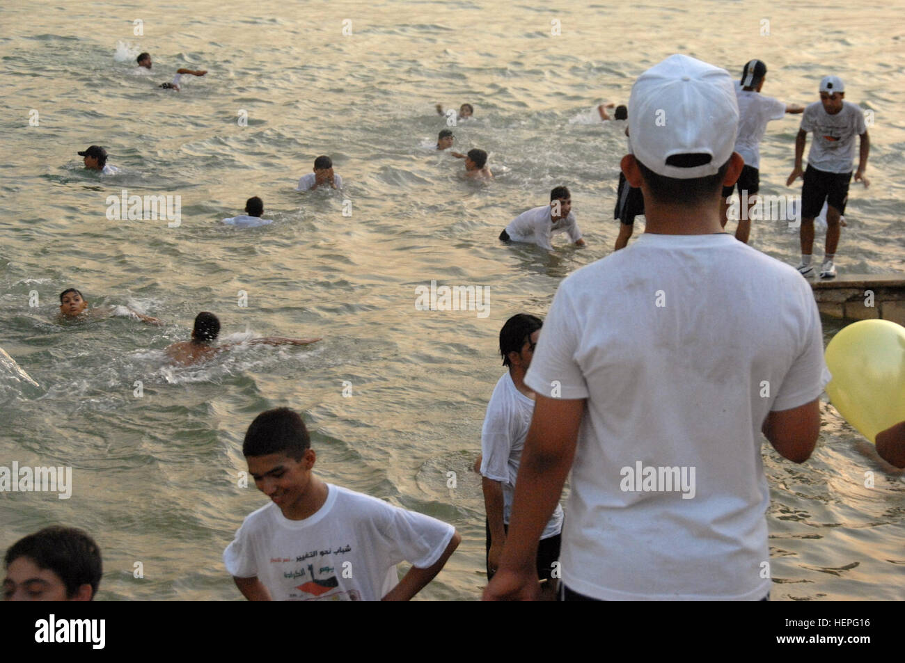 A large group of Iraqi boys enjoy swimming near the fountain at Jadriya ...