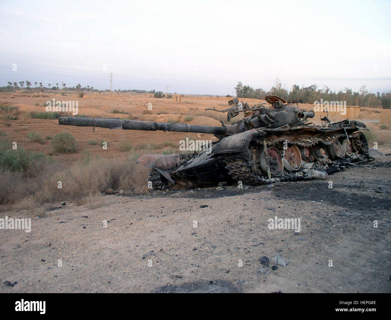 A destroyed Iraqi T-72 Main Battle Tank (MBT) lies along a road leading ...