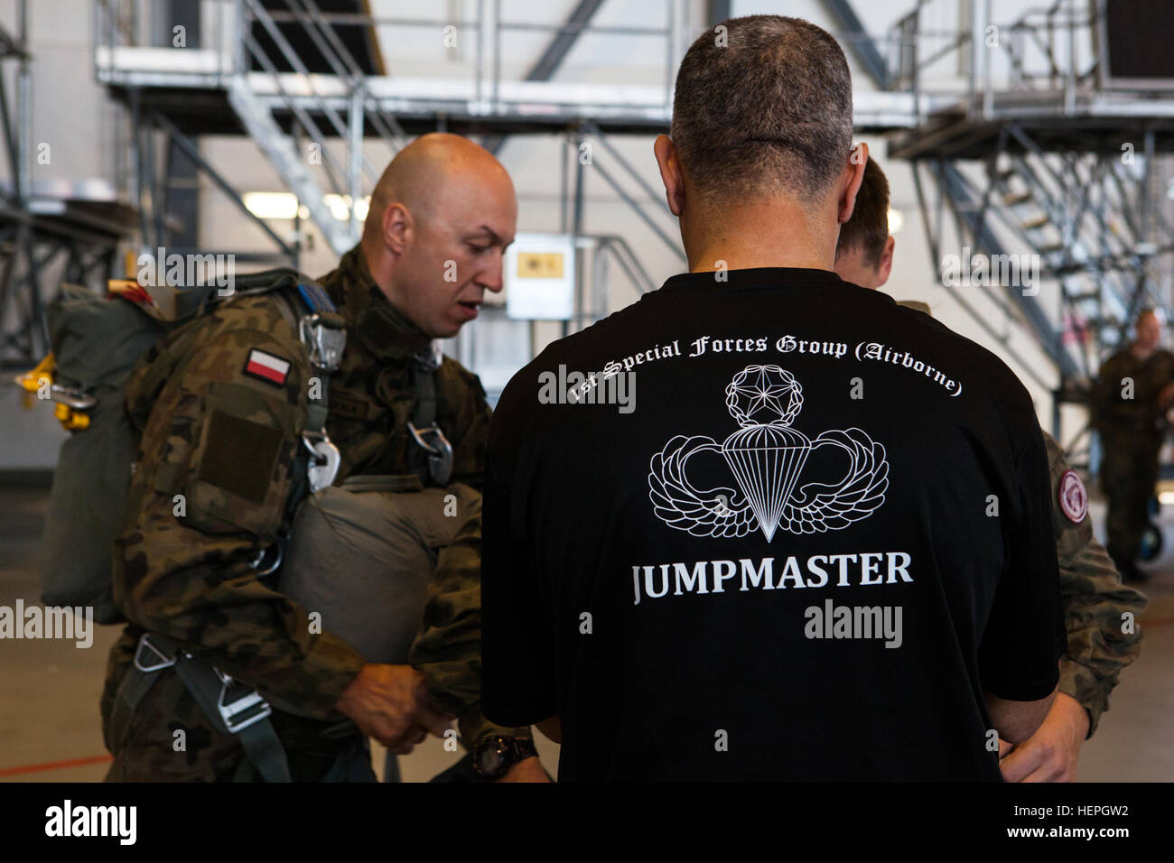 A U.S. Army jumpmaster assists a Polish paratrooper as he puts on his ...