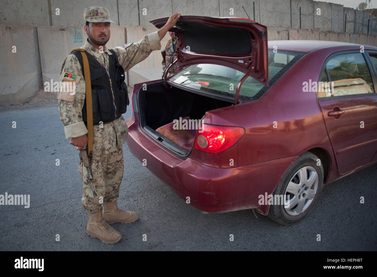 An Afghan National Civil Order Police officer searches the a vehicle at ...