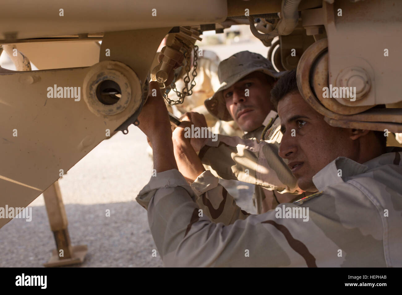 Iraqi army engineers work to remove a pin from a mine roller during ...