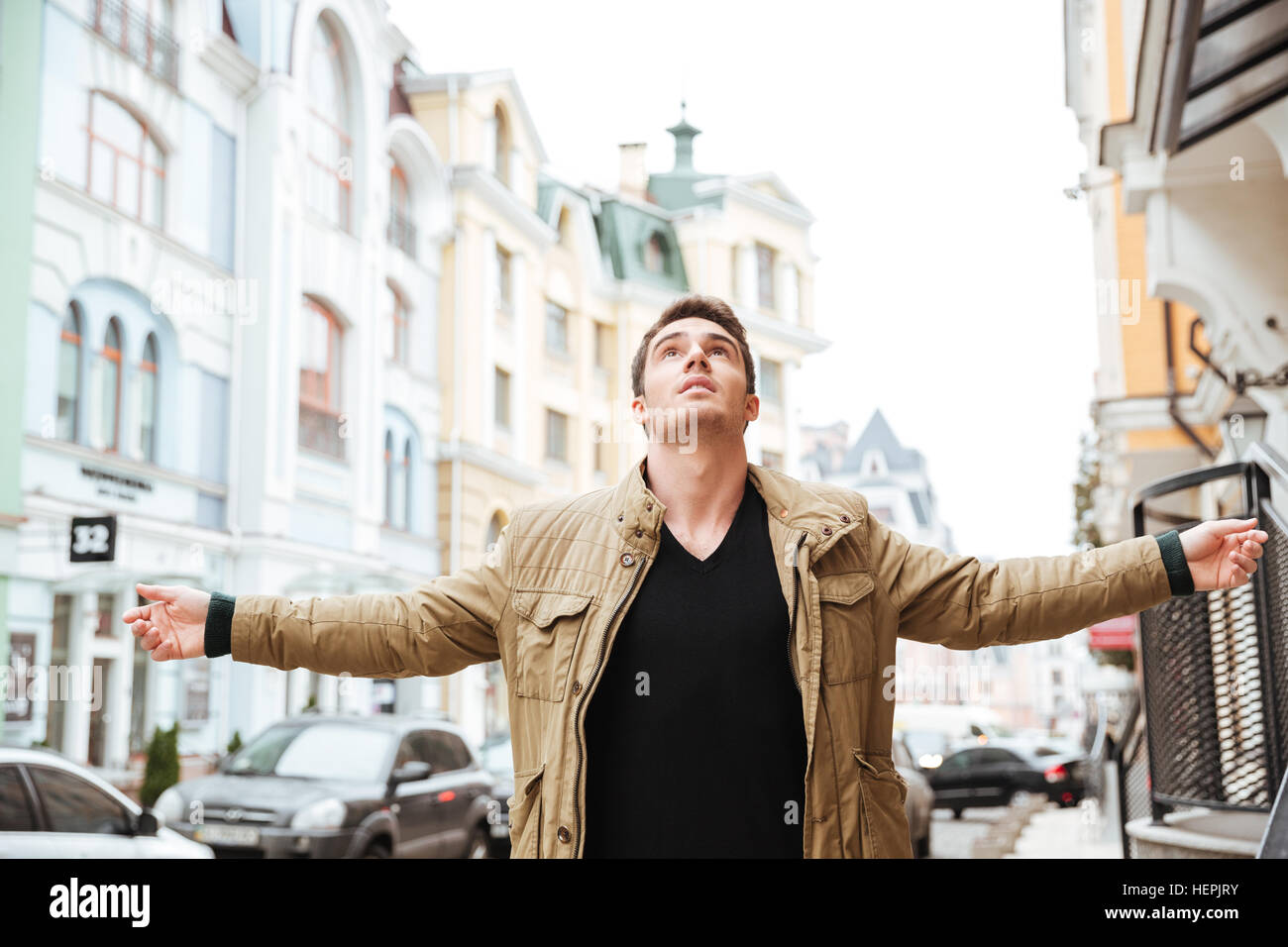 Picture of handsome young man walking on the street and looking up to ...