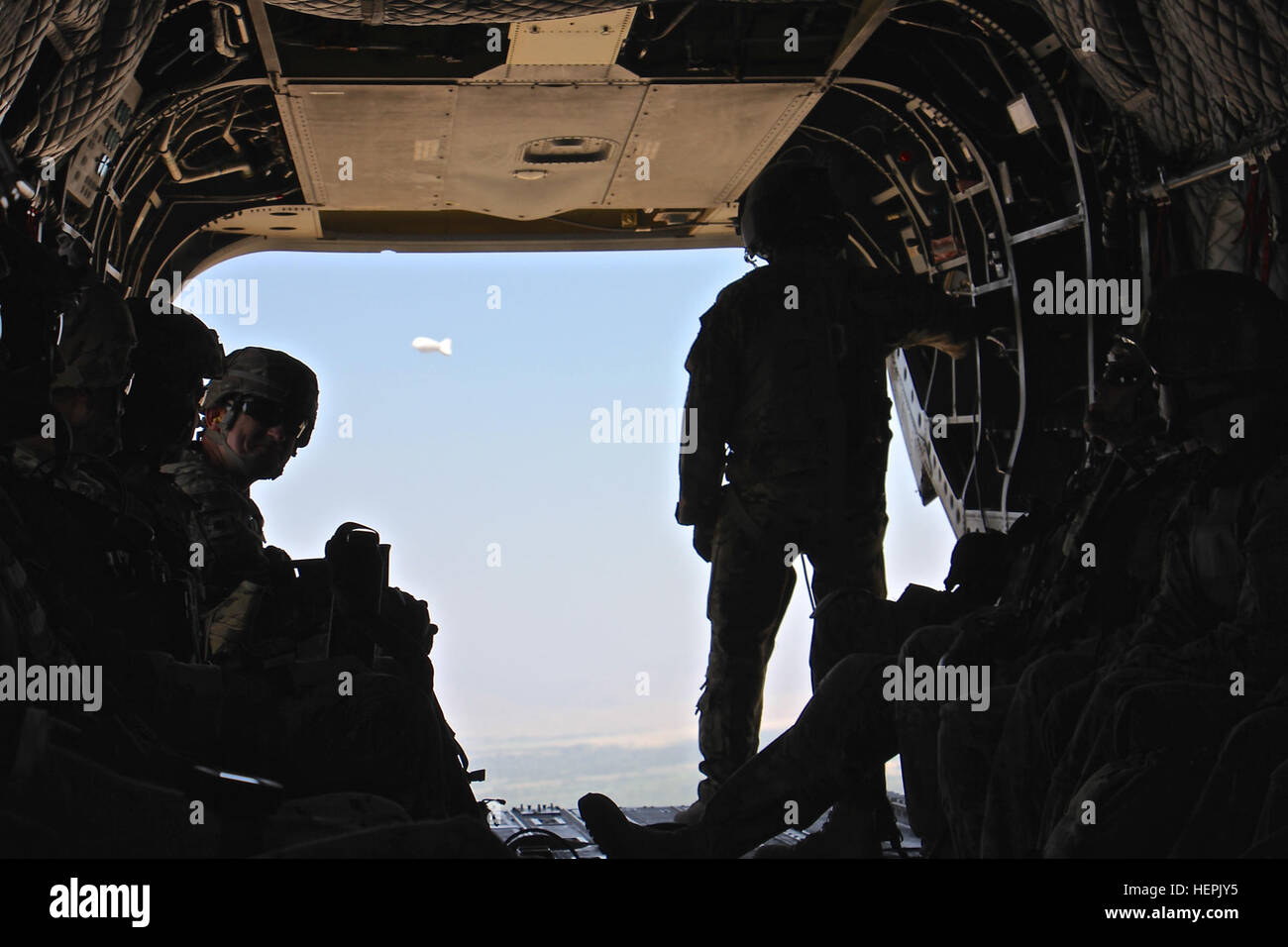 A CH-47 Chinook helicopter air crew member watches from the ramp as ...