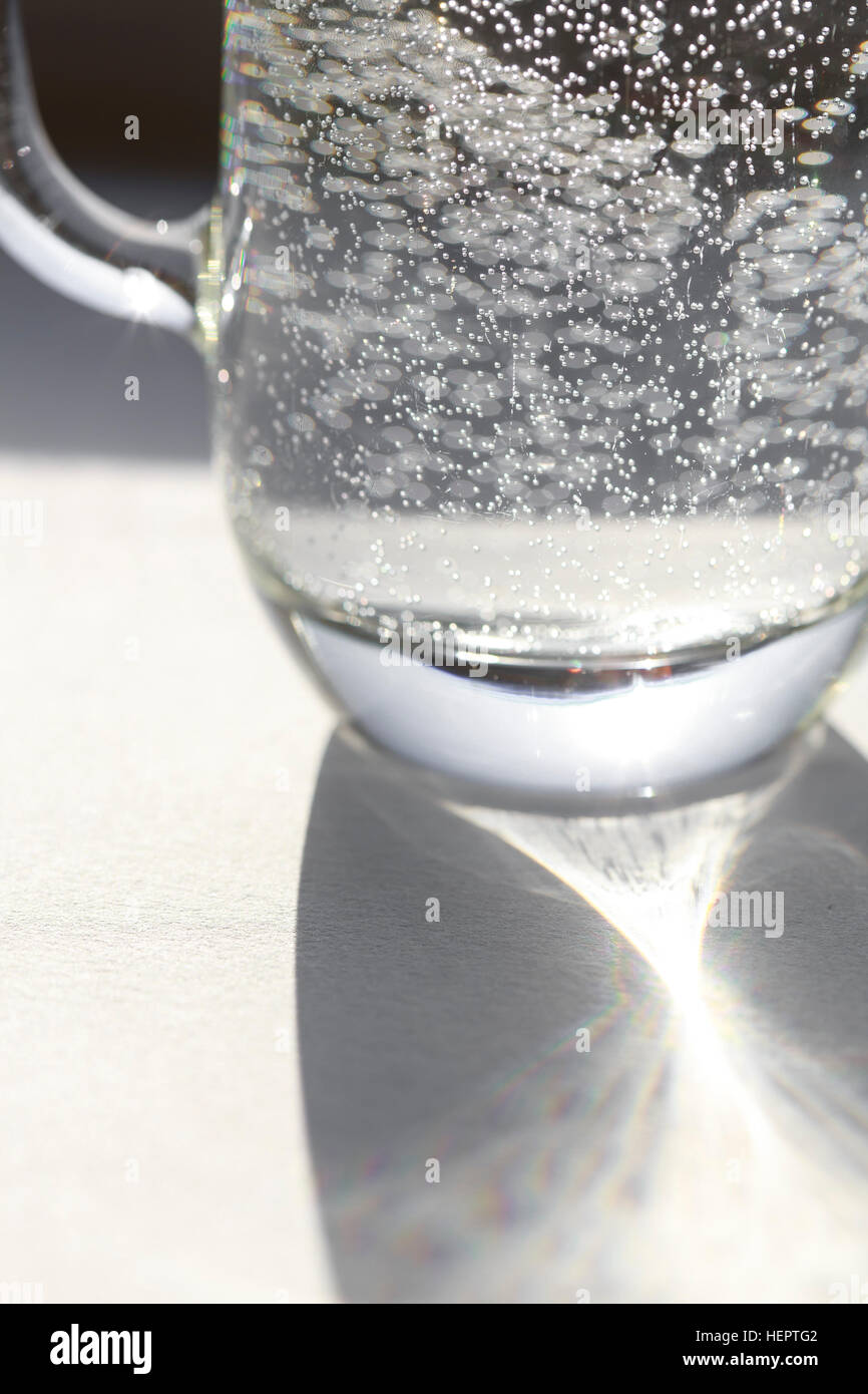 A glass of pure clean water backlit by the sun with a coating of ...