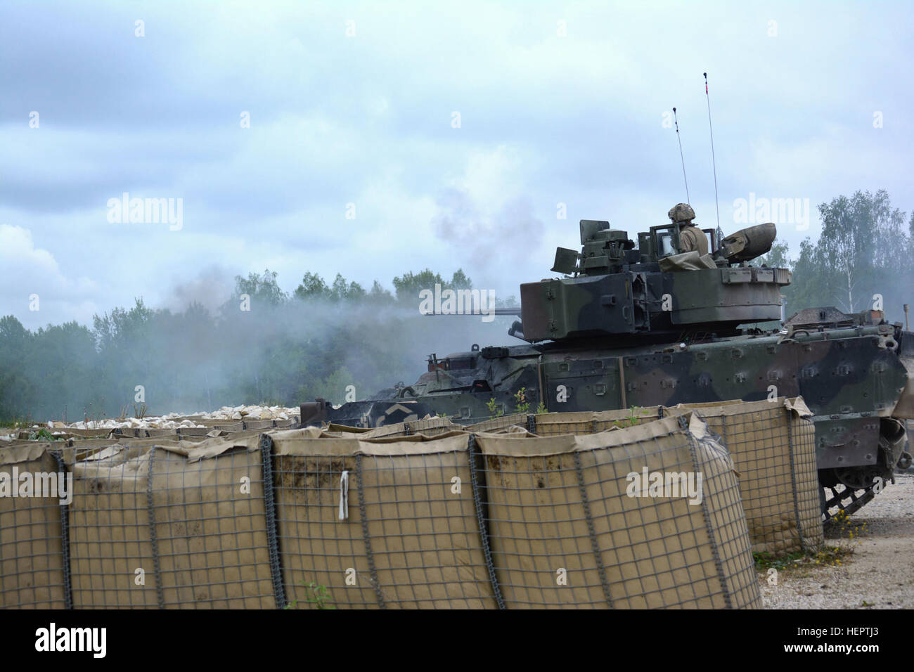 A M2A3 Bradley Fighting Vehicle engages targets with a 25mm cannon as ...